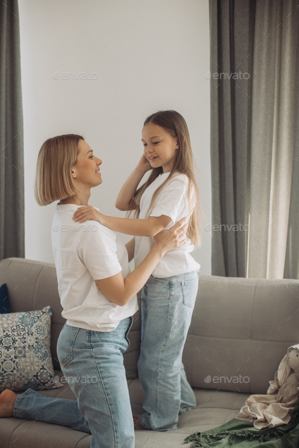 Cheerful mom playing laughing with little daughter on sofa. Stock Photo by dmytros9